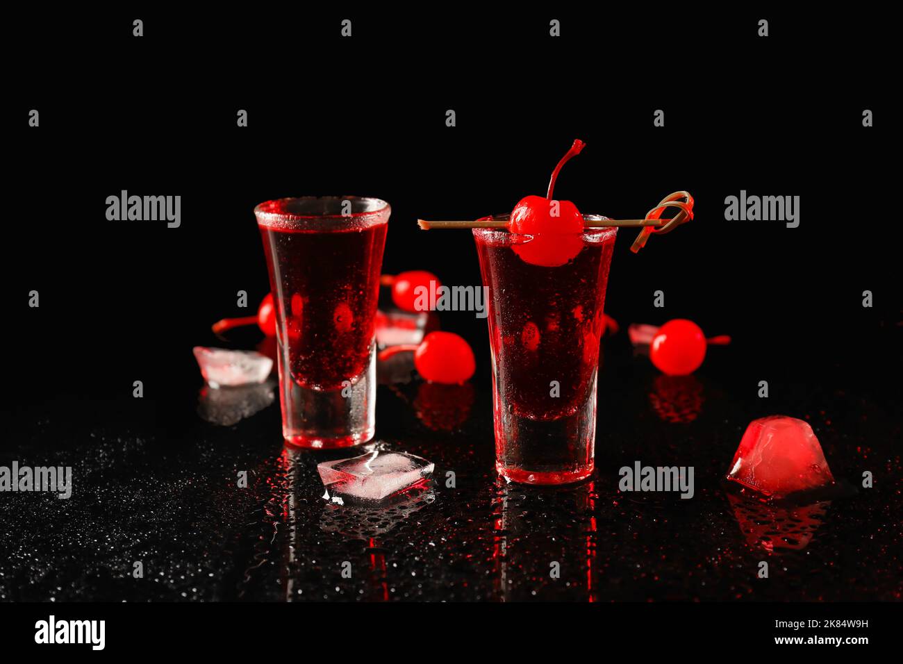 Delicious shot cocktails, cherries and ice cubes on dark background ...