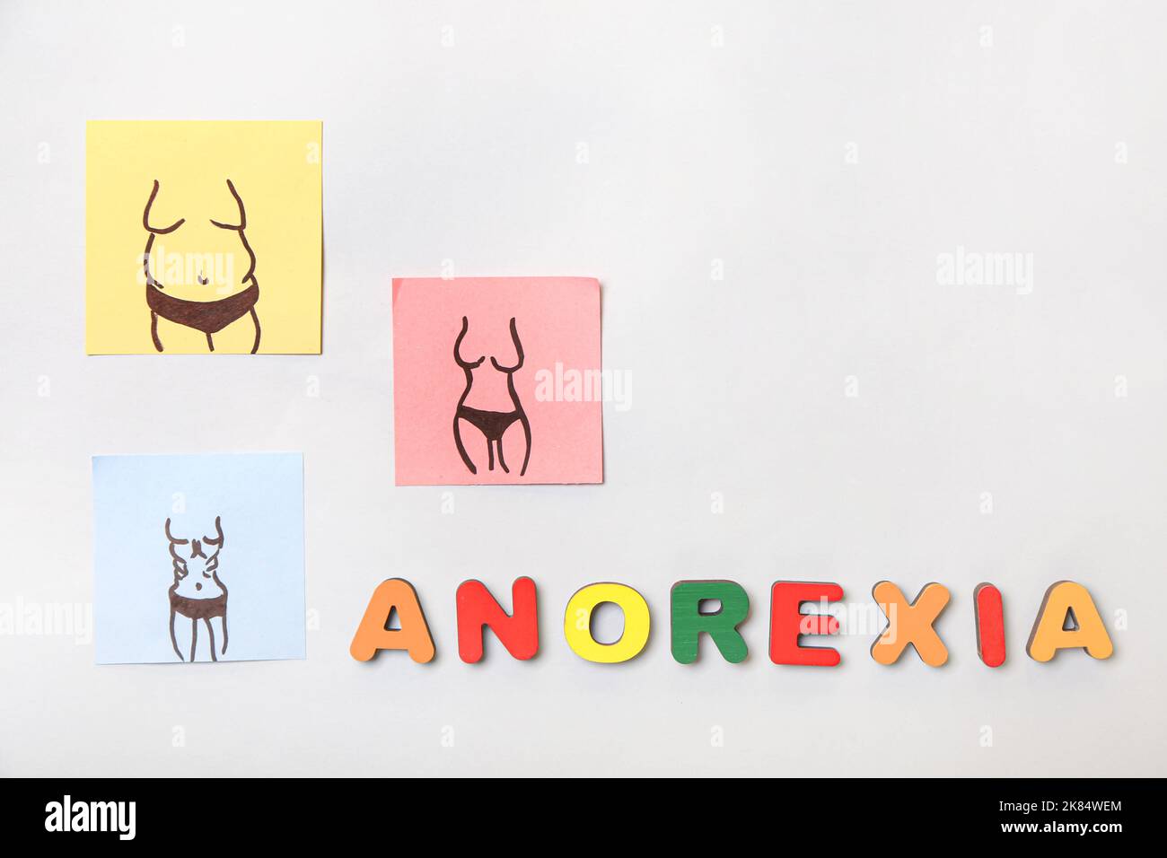 Papers with female body drawing and word ANOREXIA on white background ...