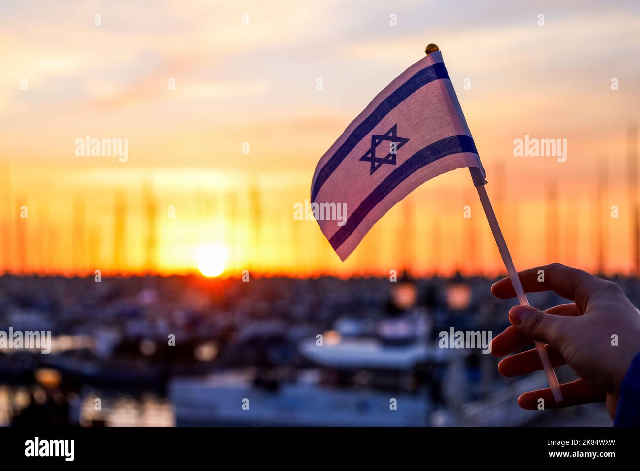 Female hand holding flag of Israel against sunset sky background Stock ...