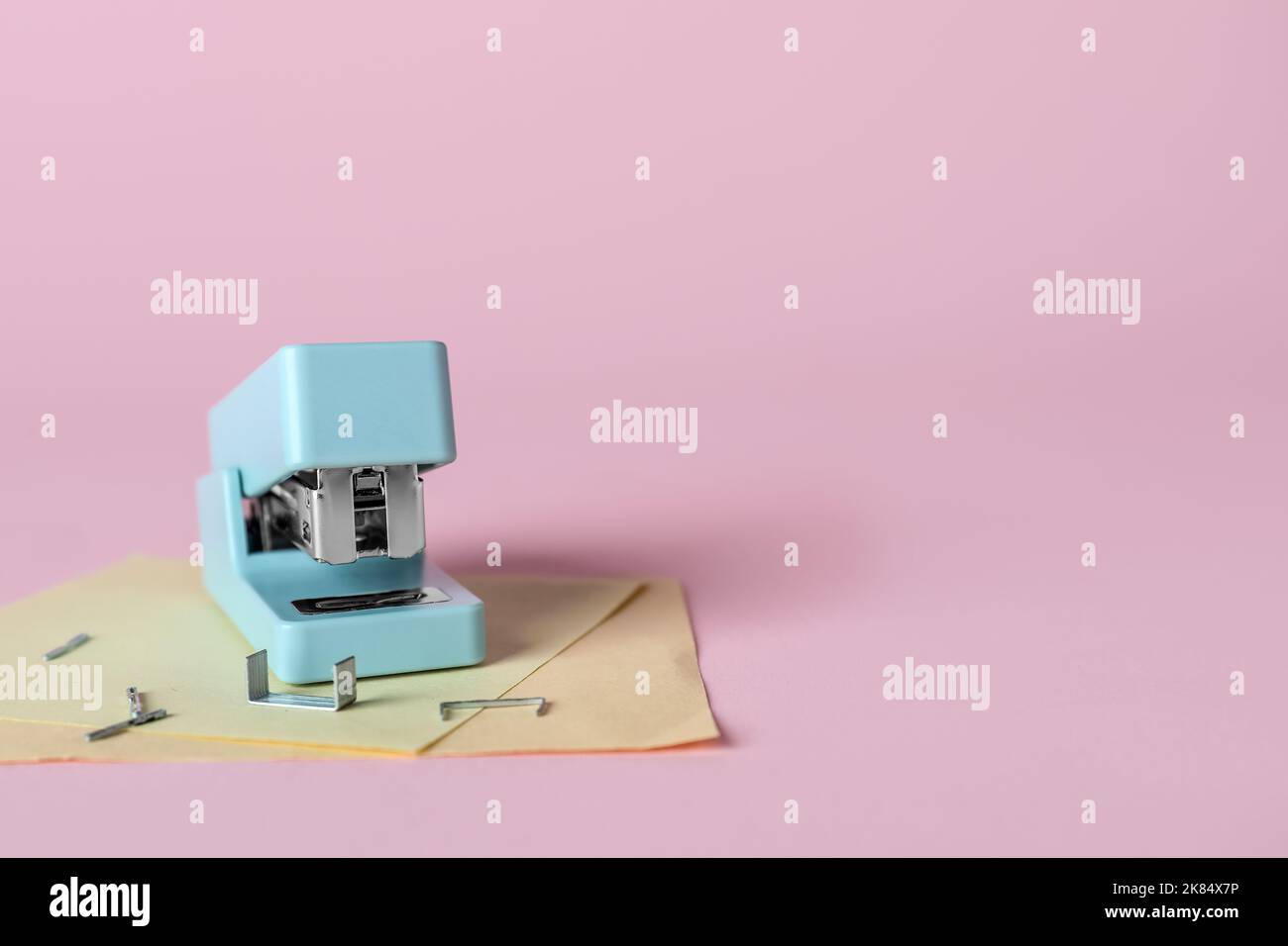 Stapler with sticky notes and staples on pink background Stock Photo ...