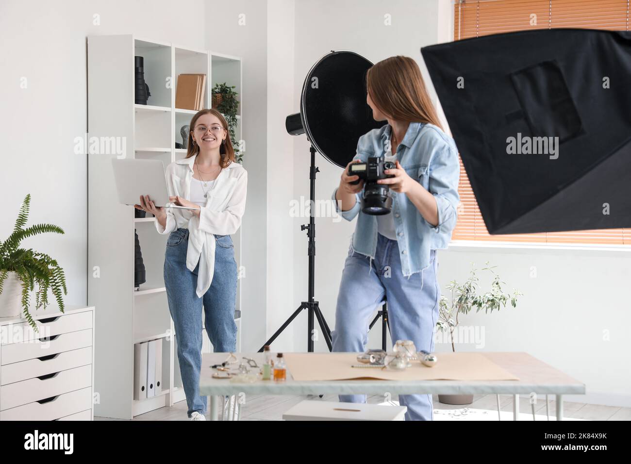 Female photographer with assistant working in modern studio Stock Photo ...