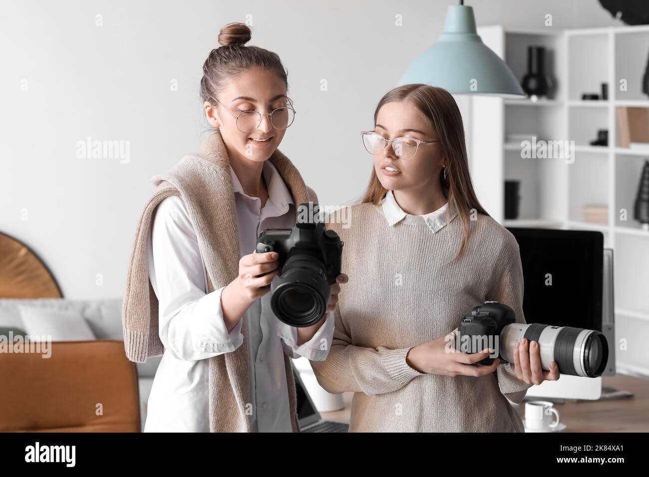 Female photographer and her assistant working in modern studio Stock ...