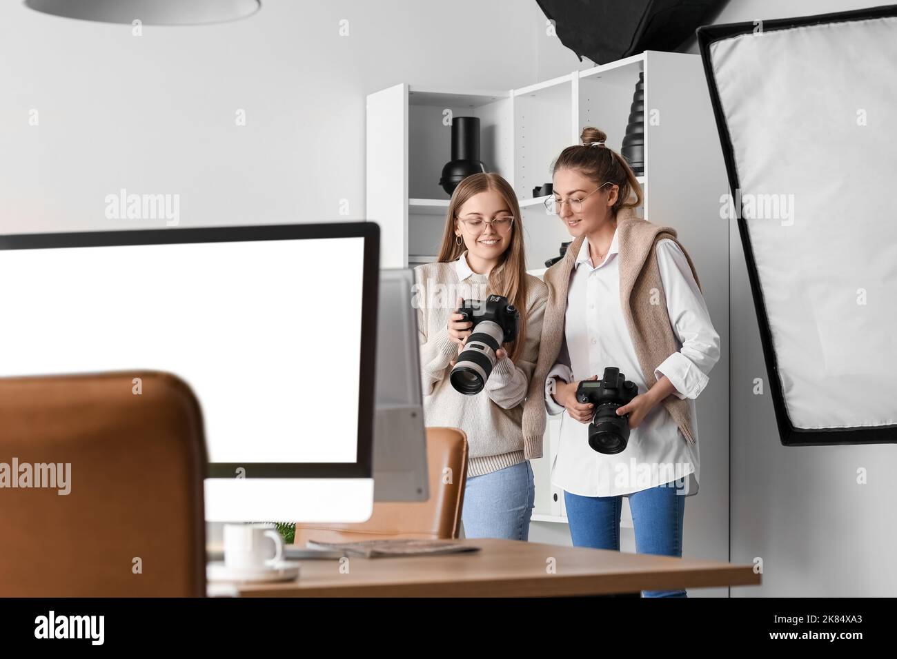 Female photographer and her assistant working in modern studio Stock ...