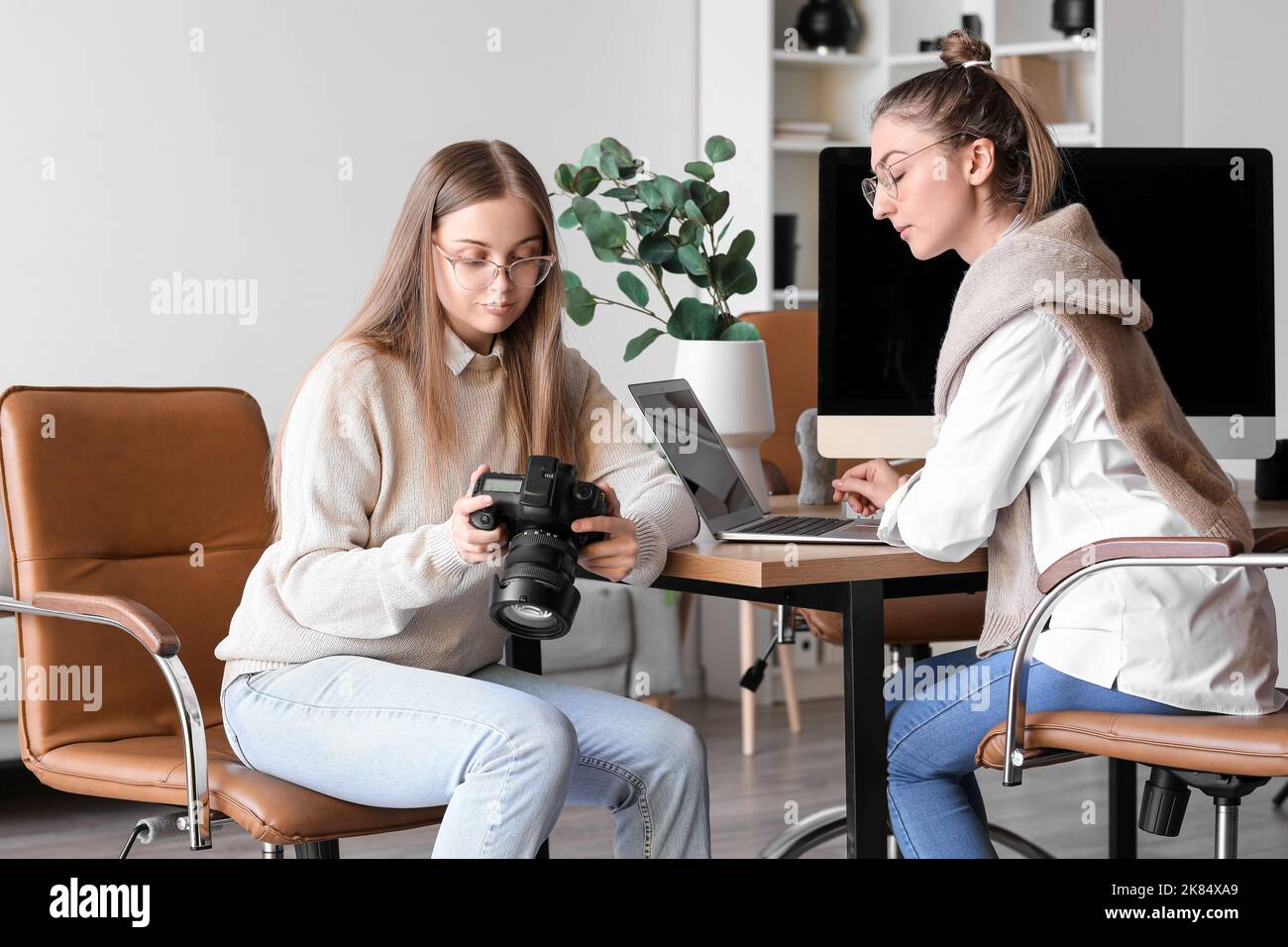 Female photographer and her assistant working in modern studio Stock ...