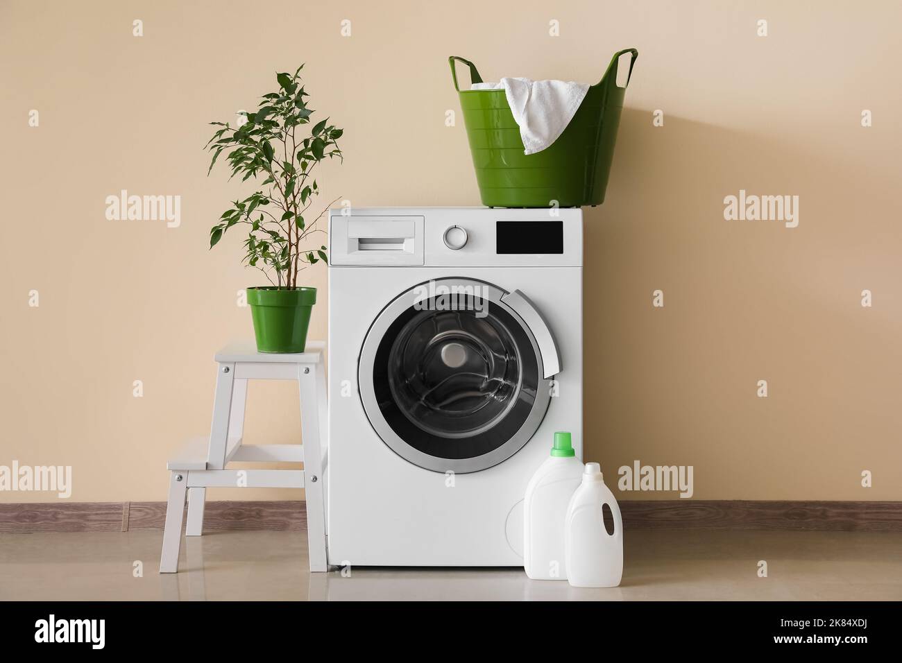 Washing machine with laundry basket, houseplant on stepladder and ...