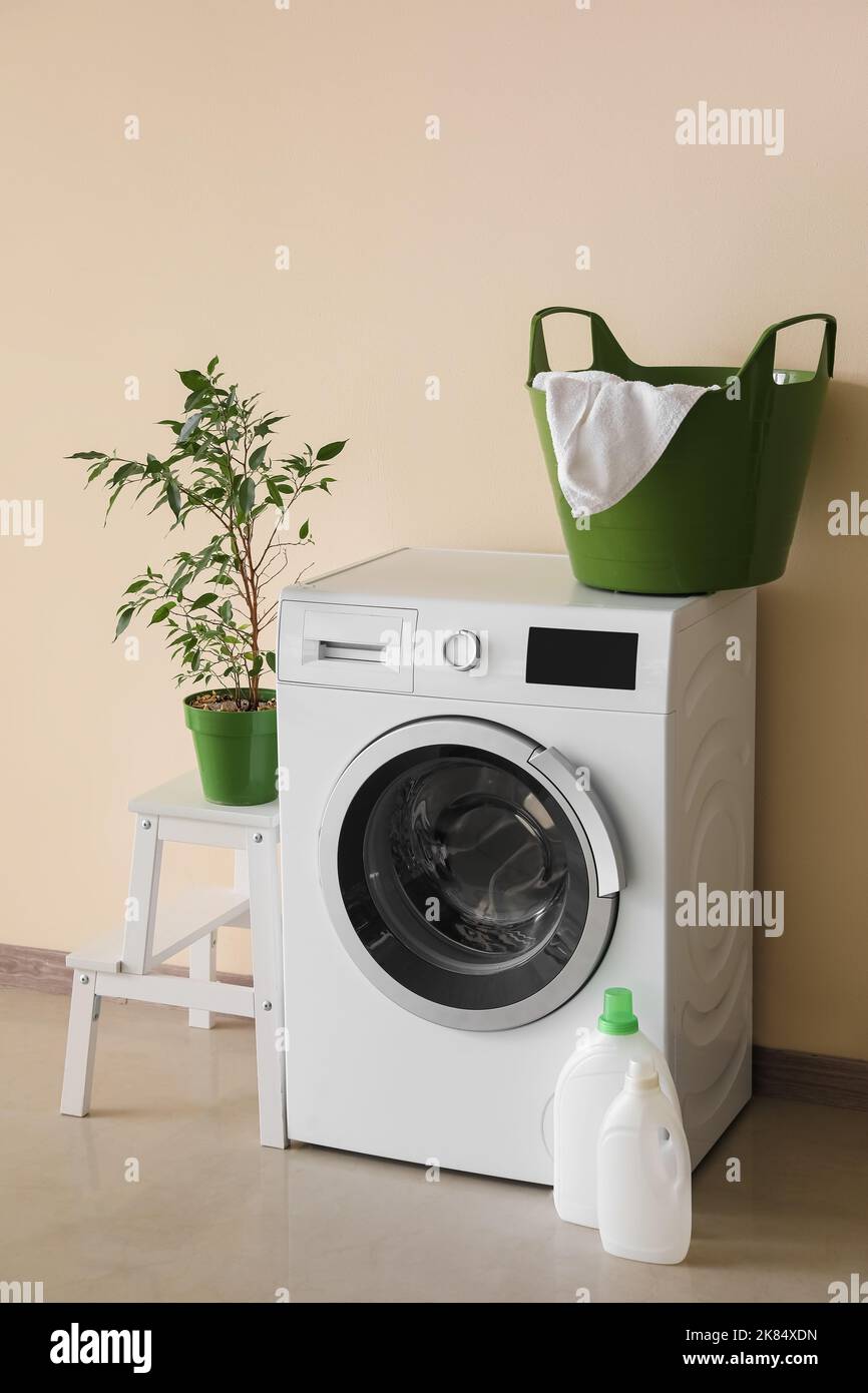 Washing machine with laundry basket, houseplant on stepladder and ...