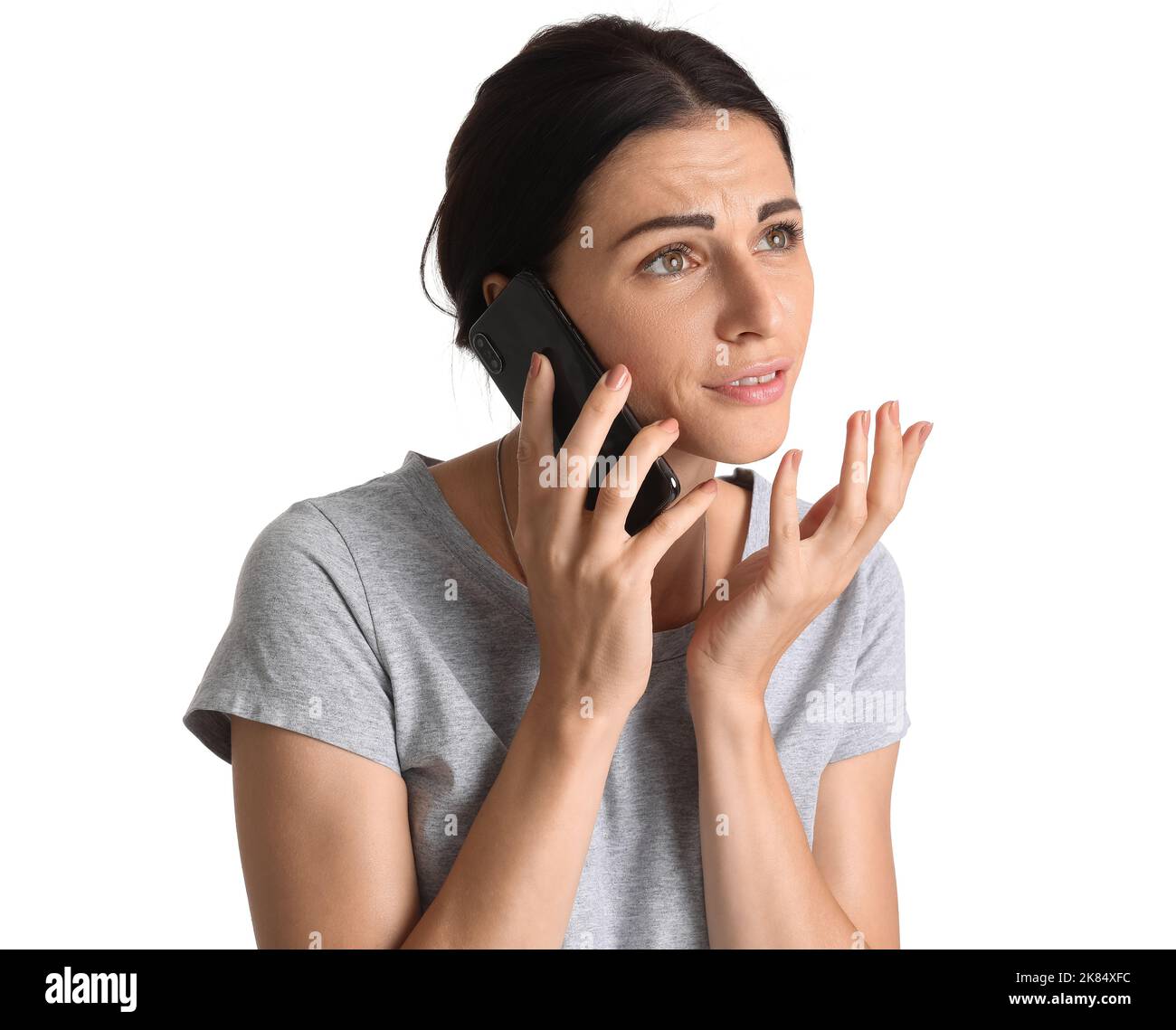 Stressed young woman talking by mobile phone on white background Stock ...