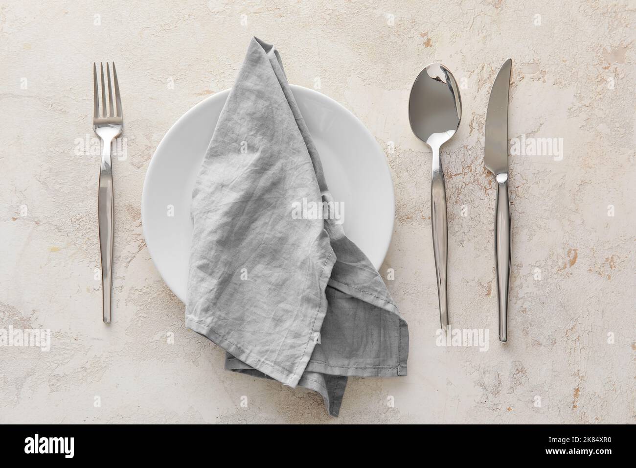 Simple table setting with napkin in plate and cutlery on light ...