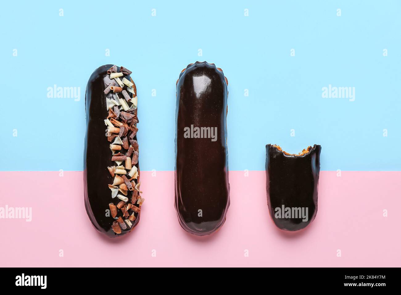 Whole and bitten chocolate eclairs on color background Stock Photo - Alamy