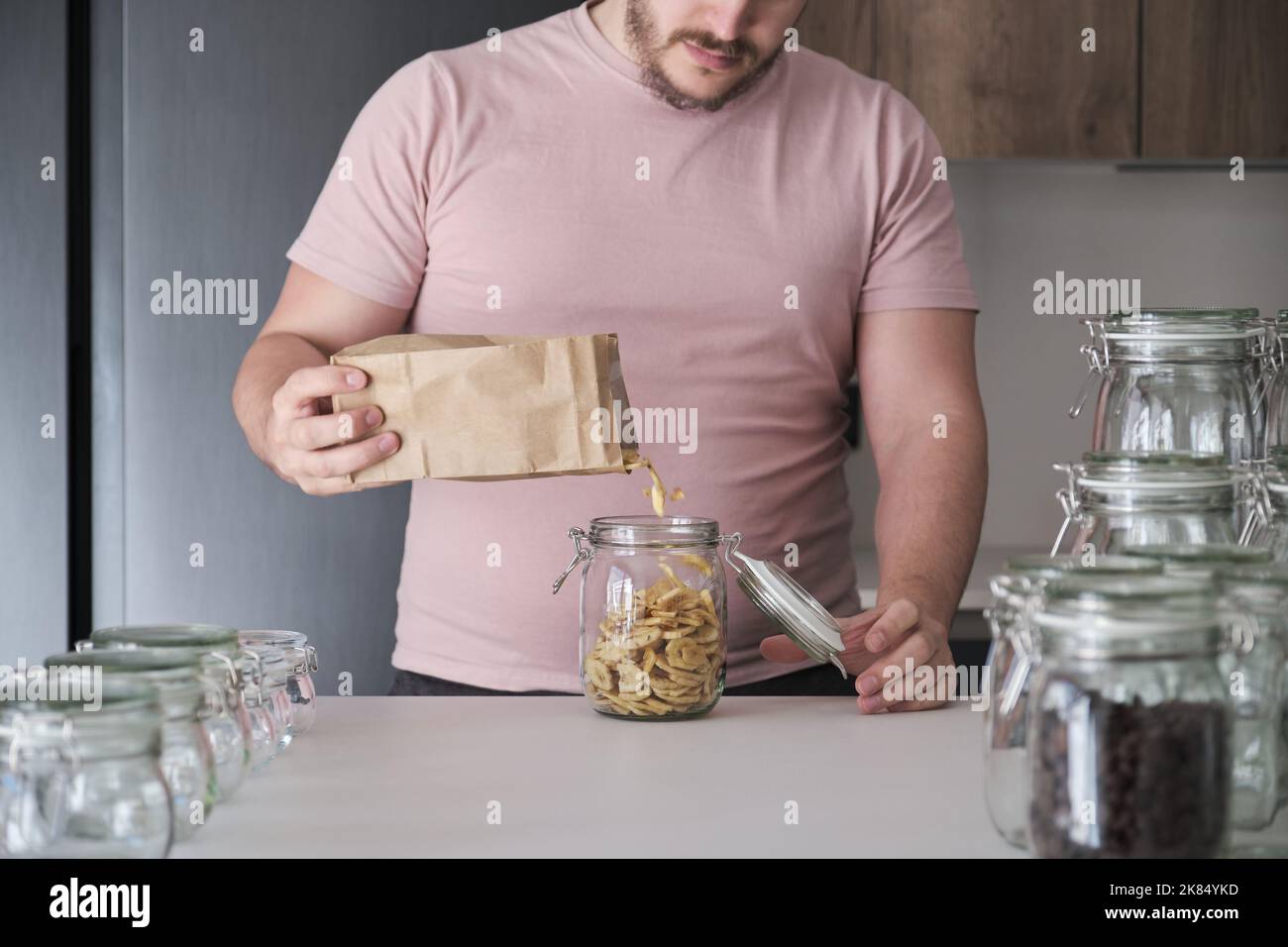 Unrecognizable latin man filling up a jar with banana chips from a ...