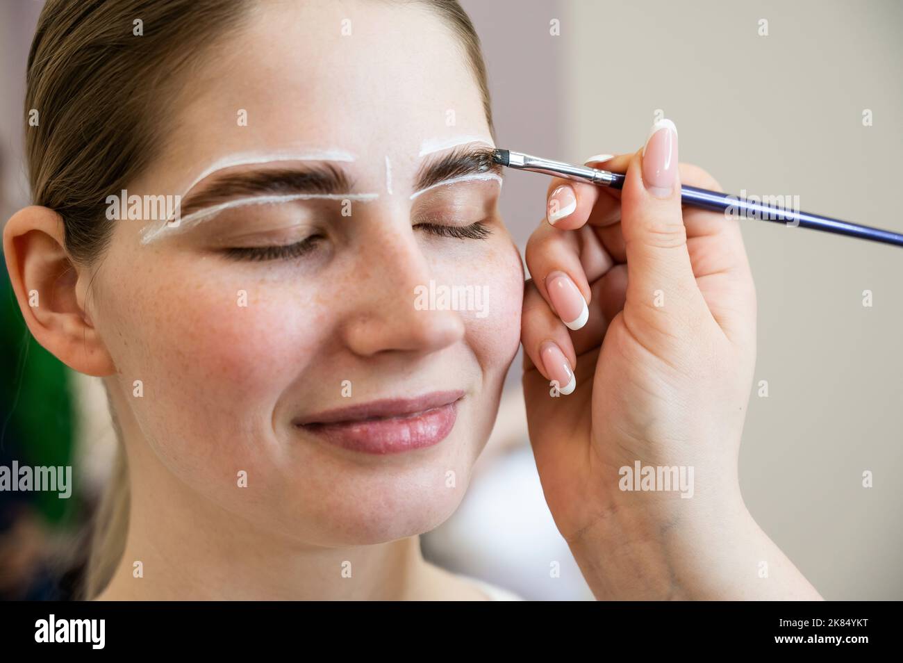 The master draws the shape of the eyebrows with white paint before ...
