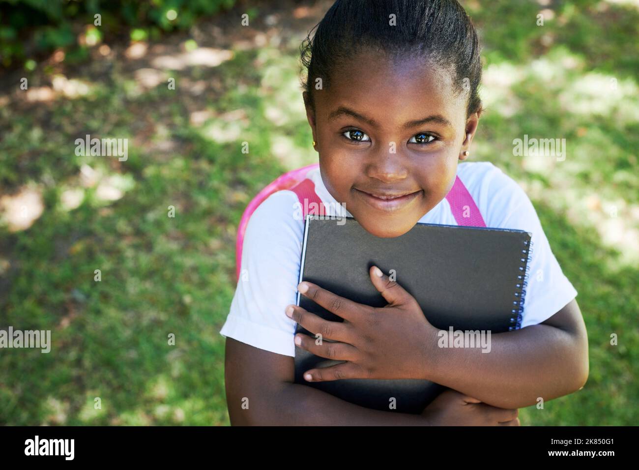 Cant forget my book. a little girl wearing a backpack while carrying ...