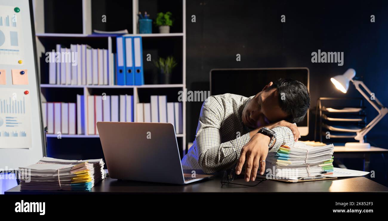 Exhausted businessman sleeping at his desk and working overtime late at ...