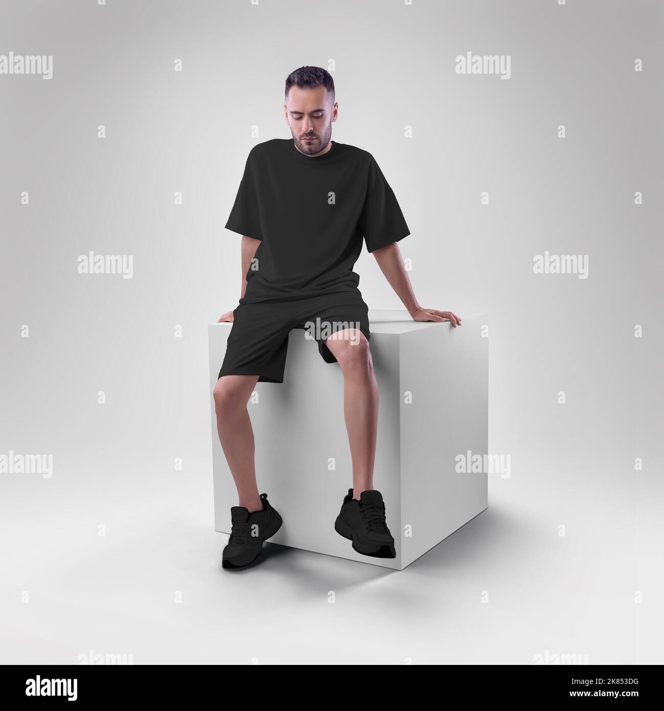 Mockup of black men's suit oversized t-shirt on shorts on man on cube. Clothing template for ...