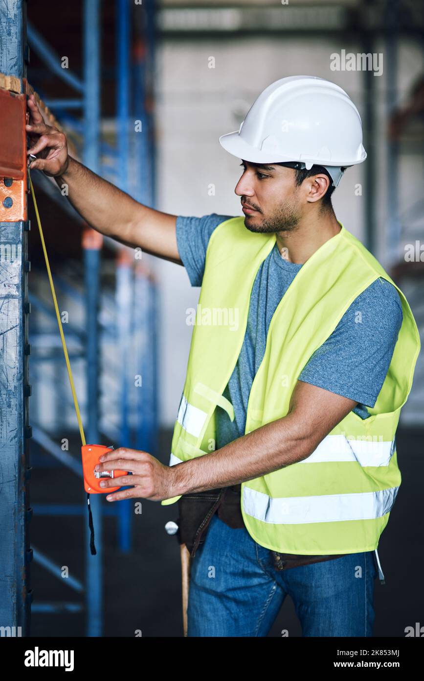 Leave no room for error. a young builder using a measuring tape at a ...