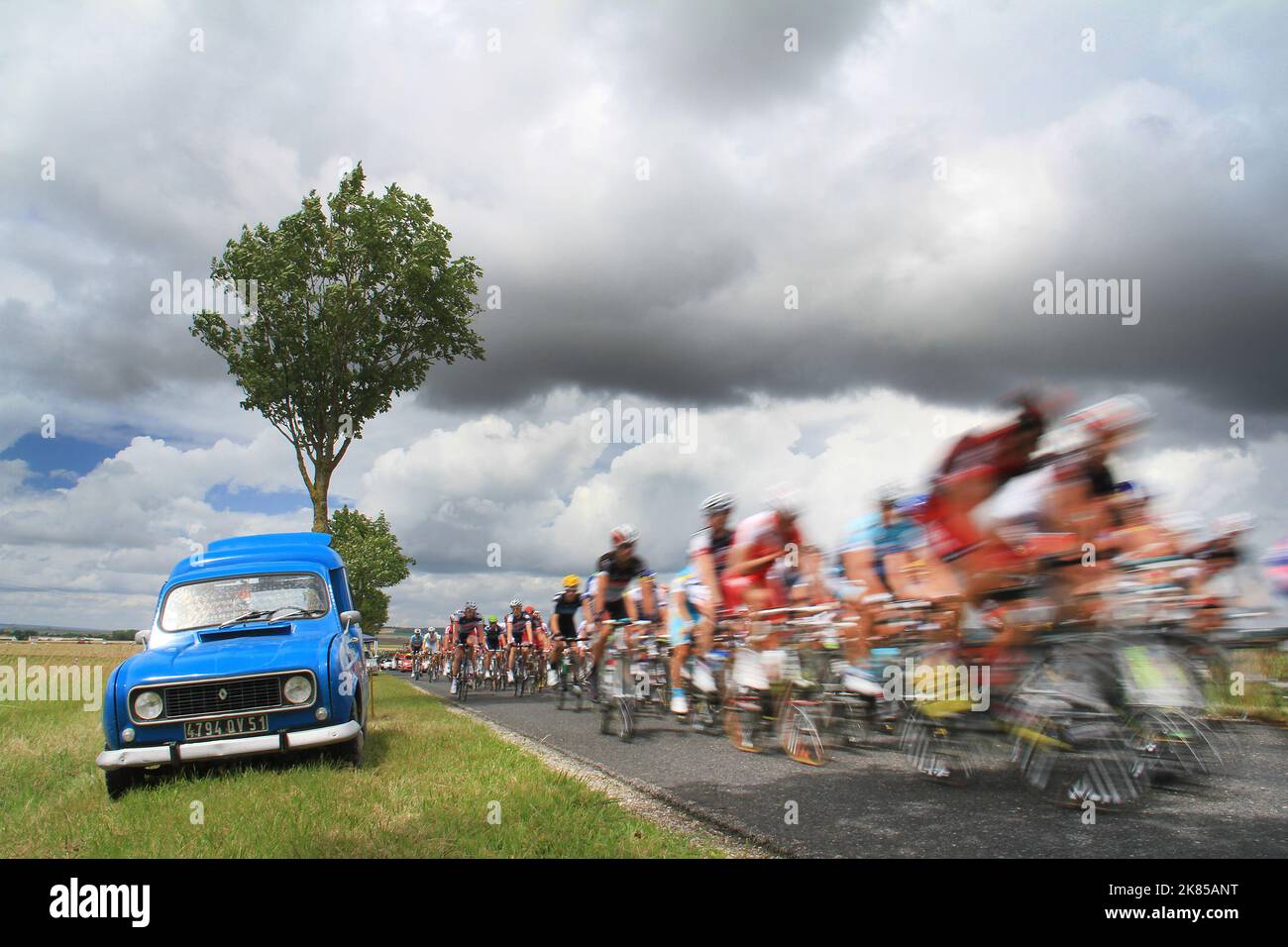 The peloton ride by an old Citroen car in the french countryside during ...