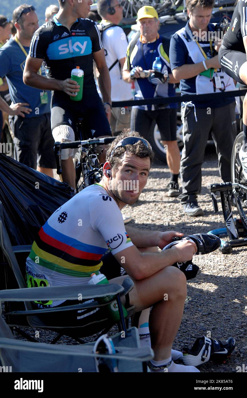 Mark Cavendish of team Sky Procycling sits whilst his team mates warm ...
