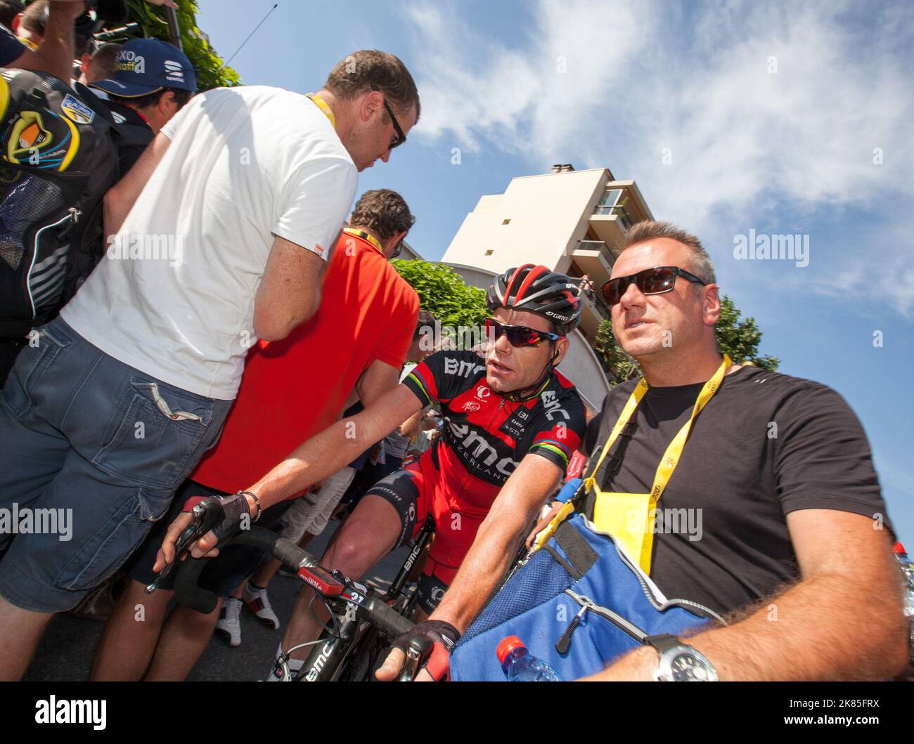 Cadel Evans gets escorted through the bustle of the finish line area ...