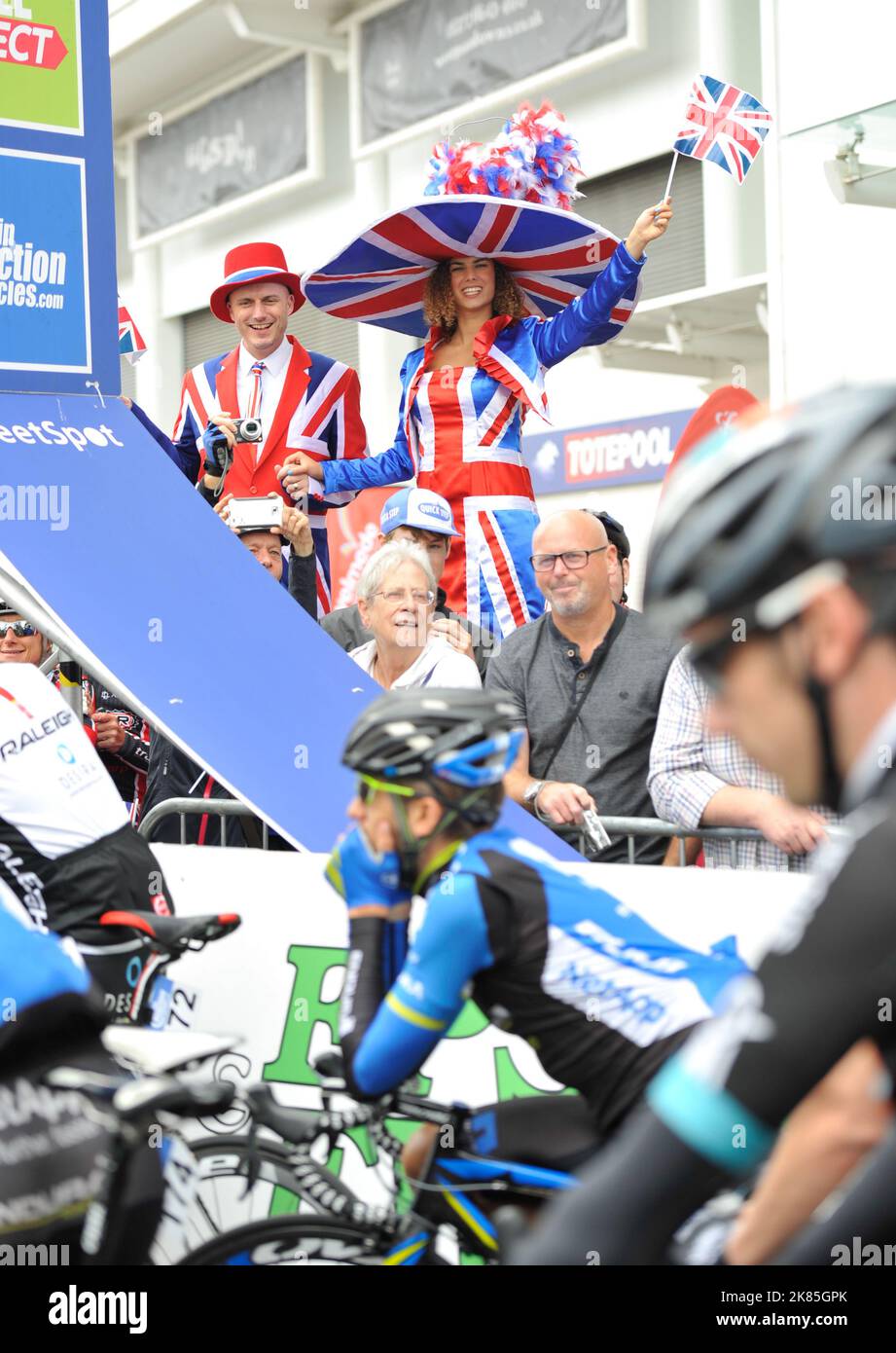 Fans dressed in union jack outfits wave flags s the riders line up to ...