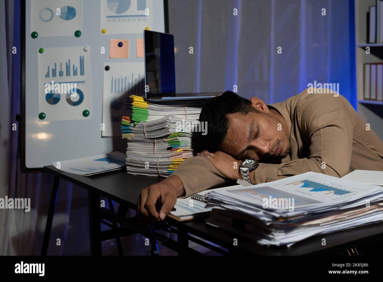 Exhausted businessman sleeping at his desk and working overtime late at ...