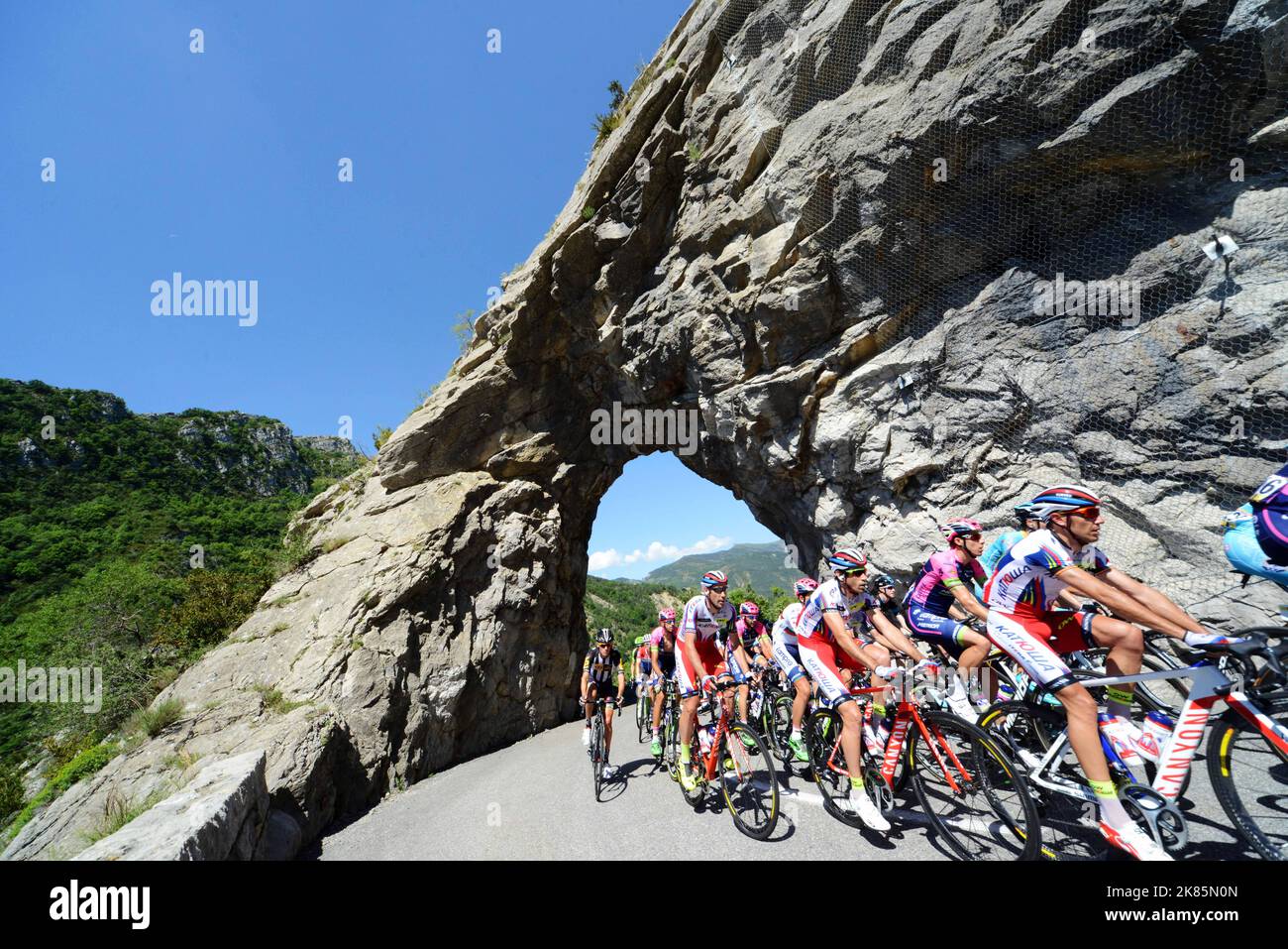 The Peloton riding through an arch in the mountainside rocks Stock ...