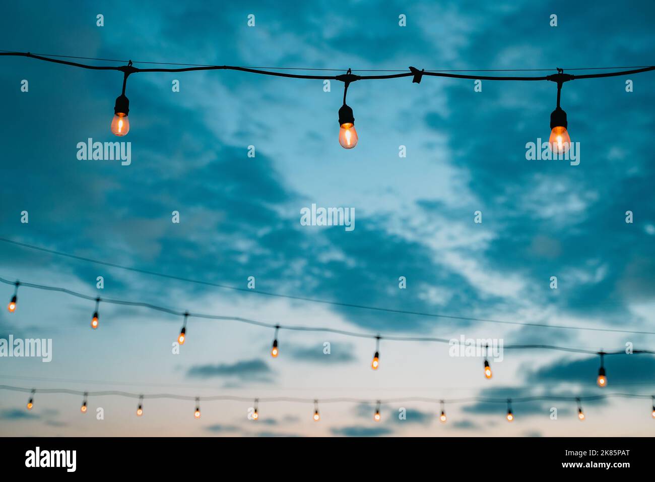 outdoor string lights in beautiful blue and orange sunset sky. Chill ...