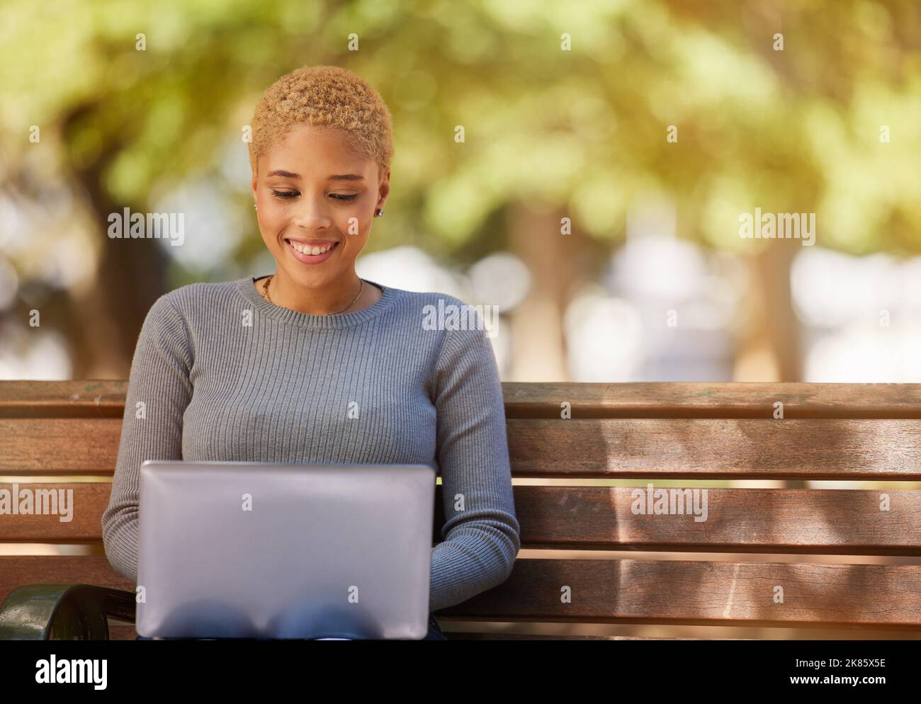 Woman, laptop and smile in park while on social media, reading or ...