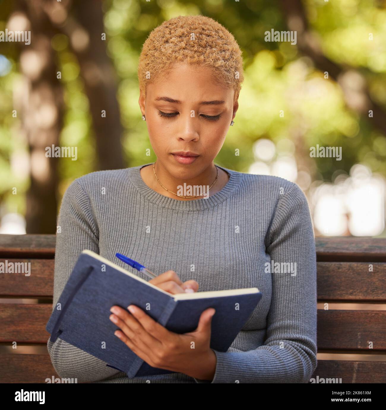 Woman, student writing in notebook and studying from diary, journal or ...
