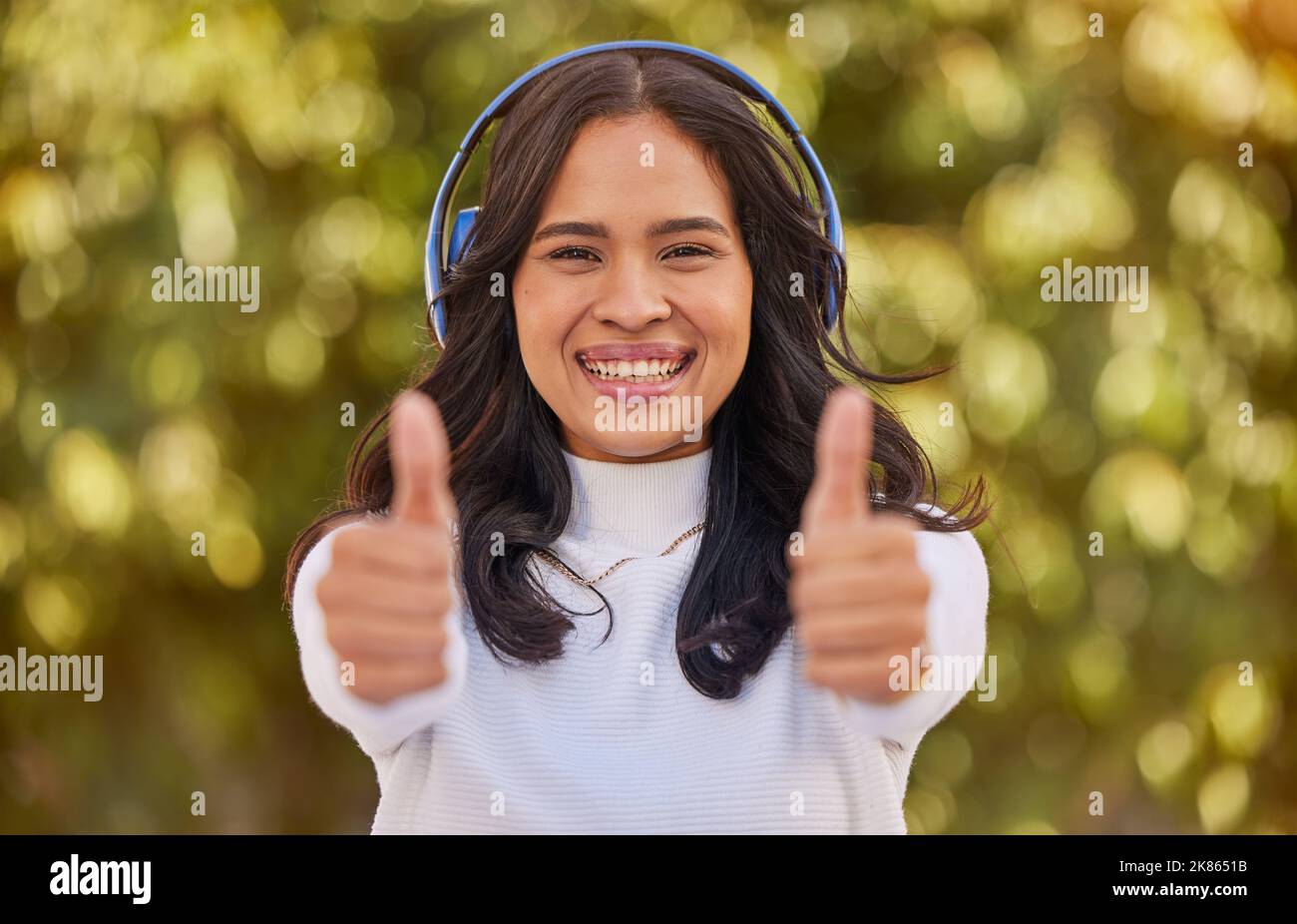 Thumbs up, relax and woman in park with headphones on listening to ...