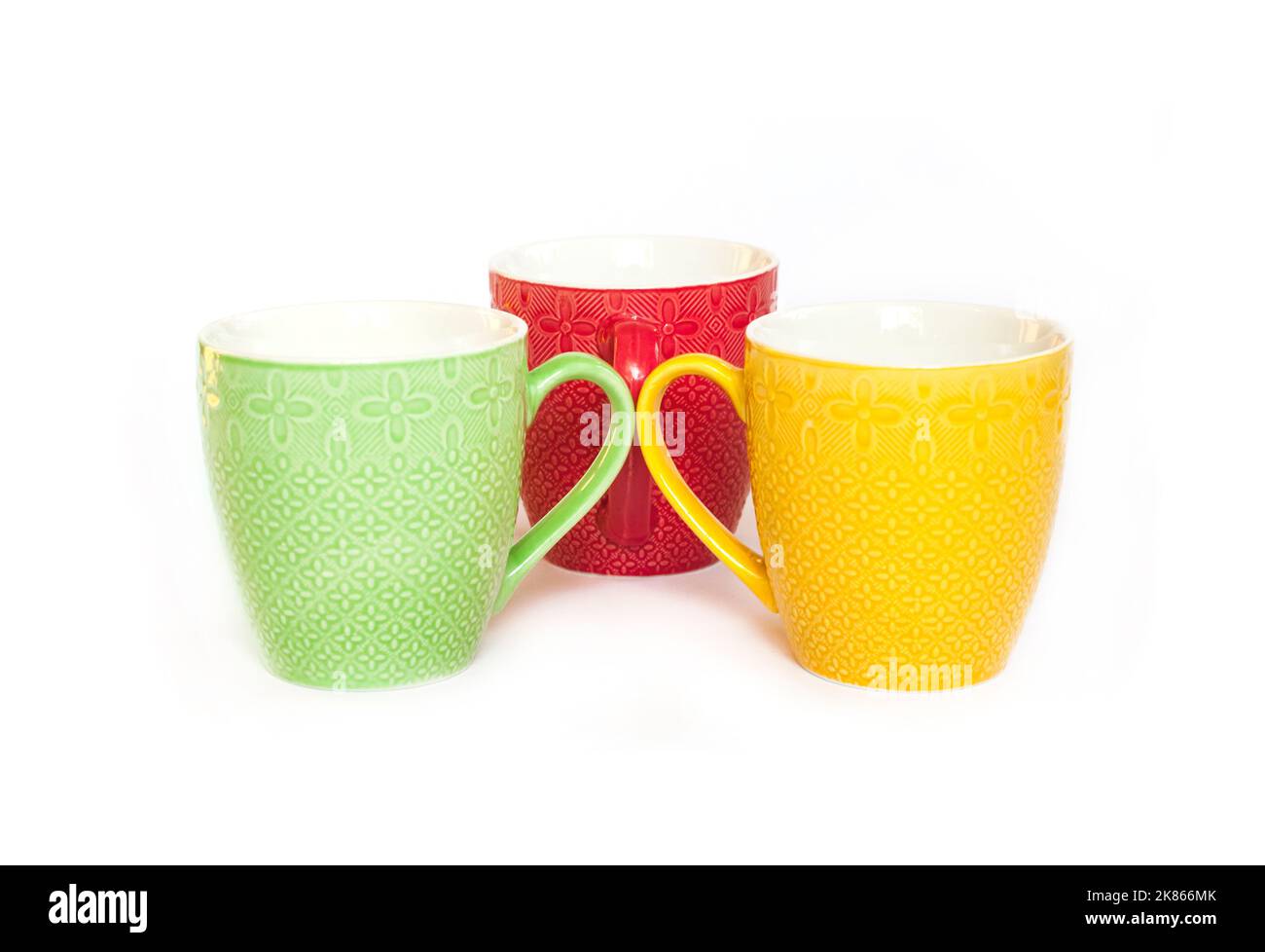 Three colorful mugs with handles turned one to the other, isolated on ...