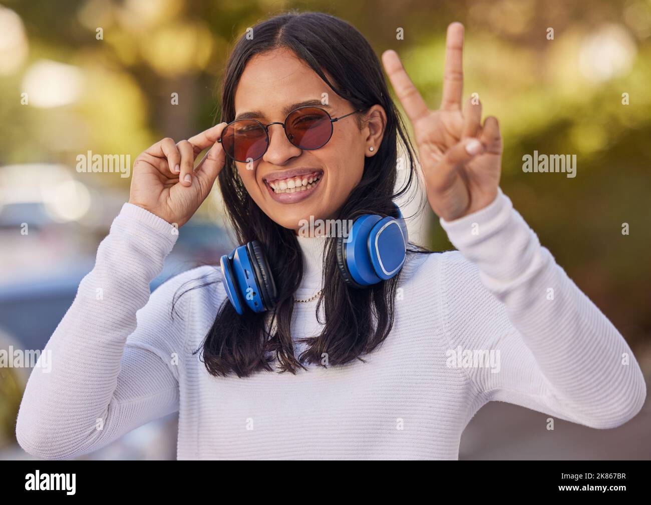 Music, headphones and peace hand sign of a woman from mexico in nature ...
