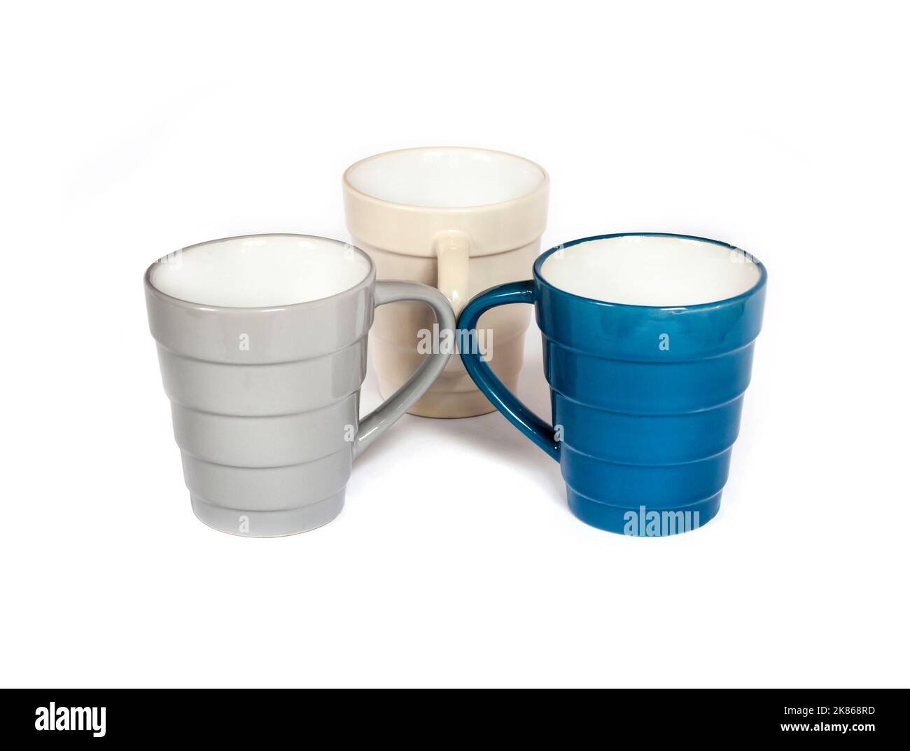 Three colorful mugs with handles turned one to the other, isolated on ...