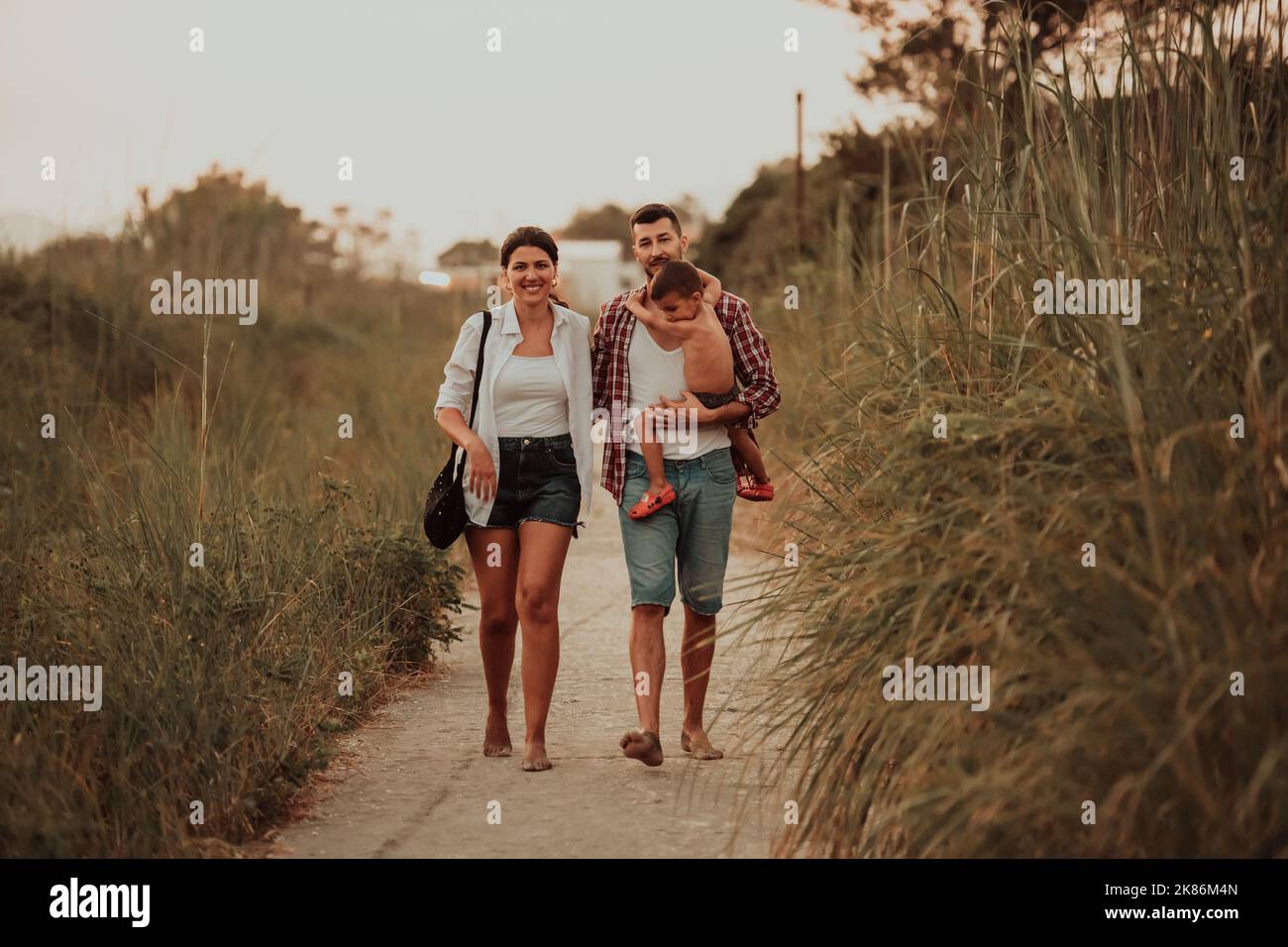 The family walks an idyllic path surrounded by tall grass. Selective ...