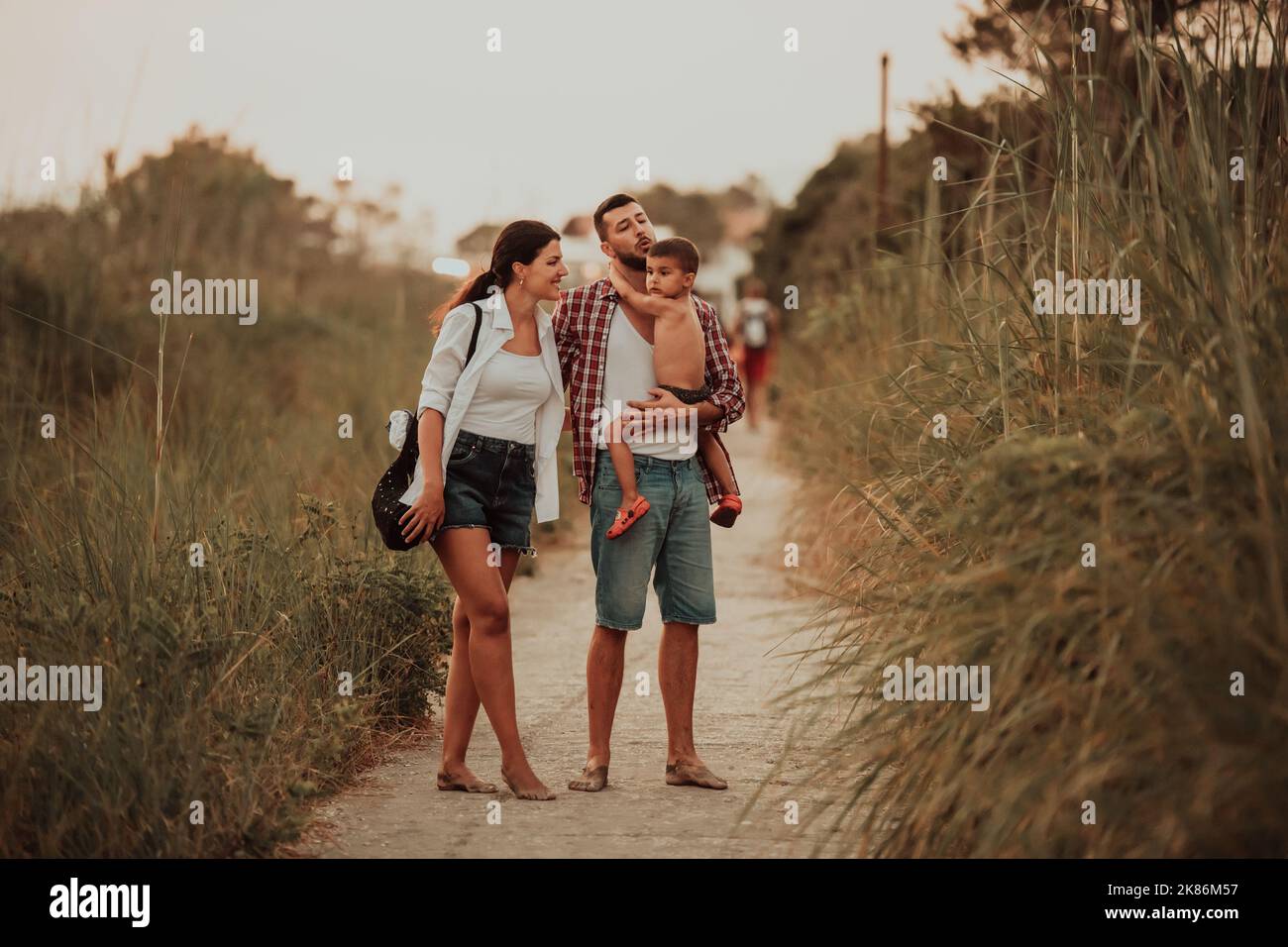The family walks an idyllic path surrounded by tall grass. Selective ...