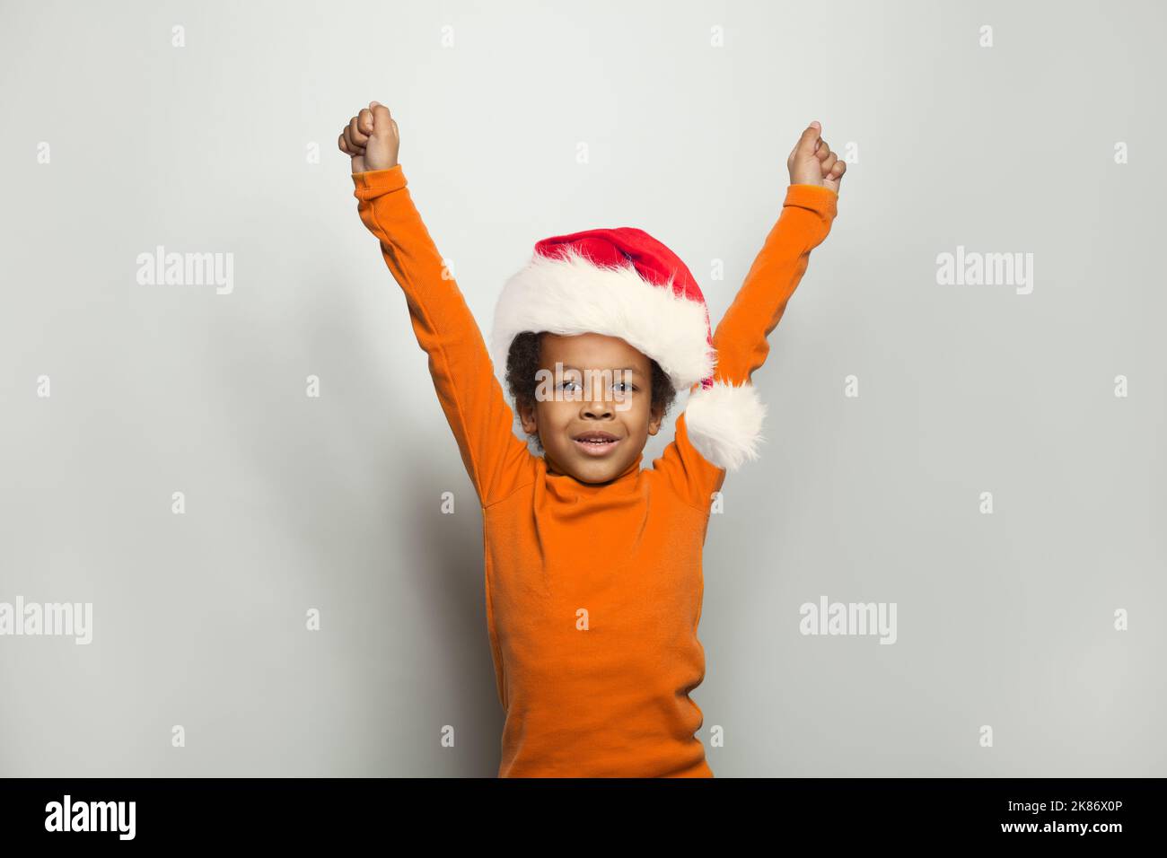 Little black kid boy in Santa hat having fun on white background Stock ...