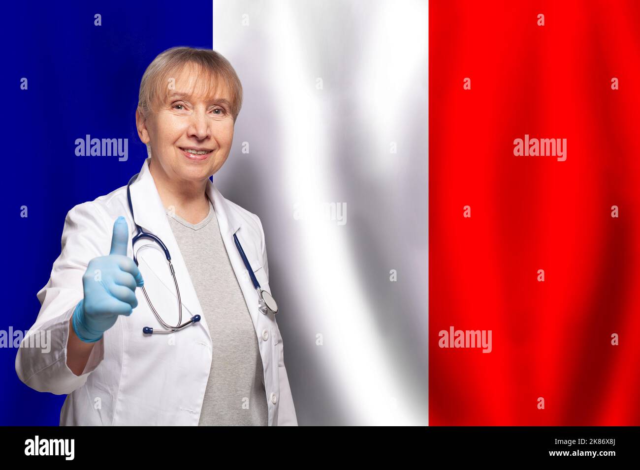French smiling mature doctor woman holding stethoscope on flag of ...