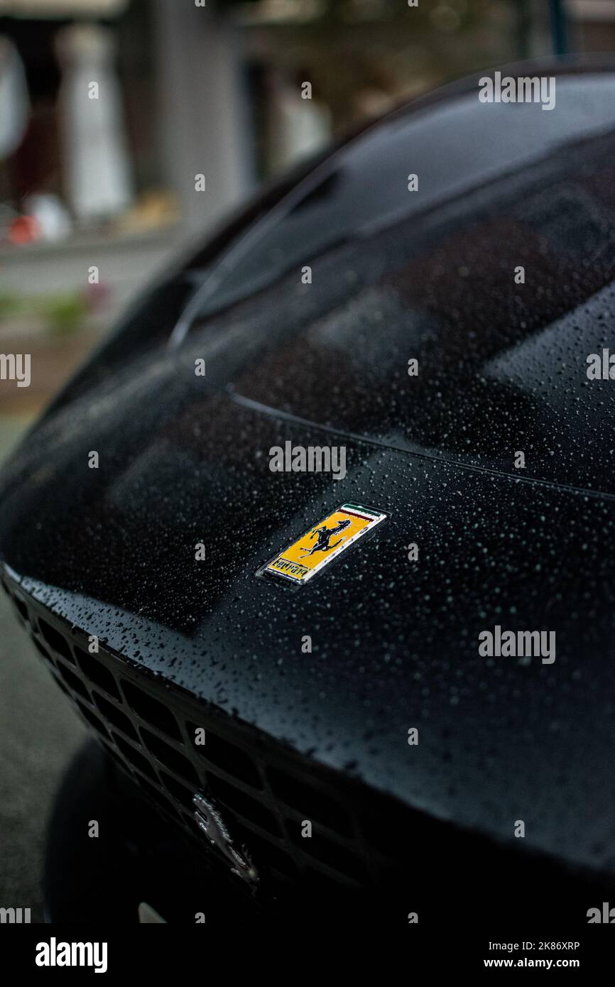 A vertical closeup of a black Ferrari logo with rain drops in Hale ...