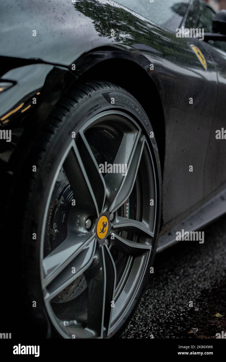 A vertical closeup of a black Ferrari wheel with rain drops in Hale ...