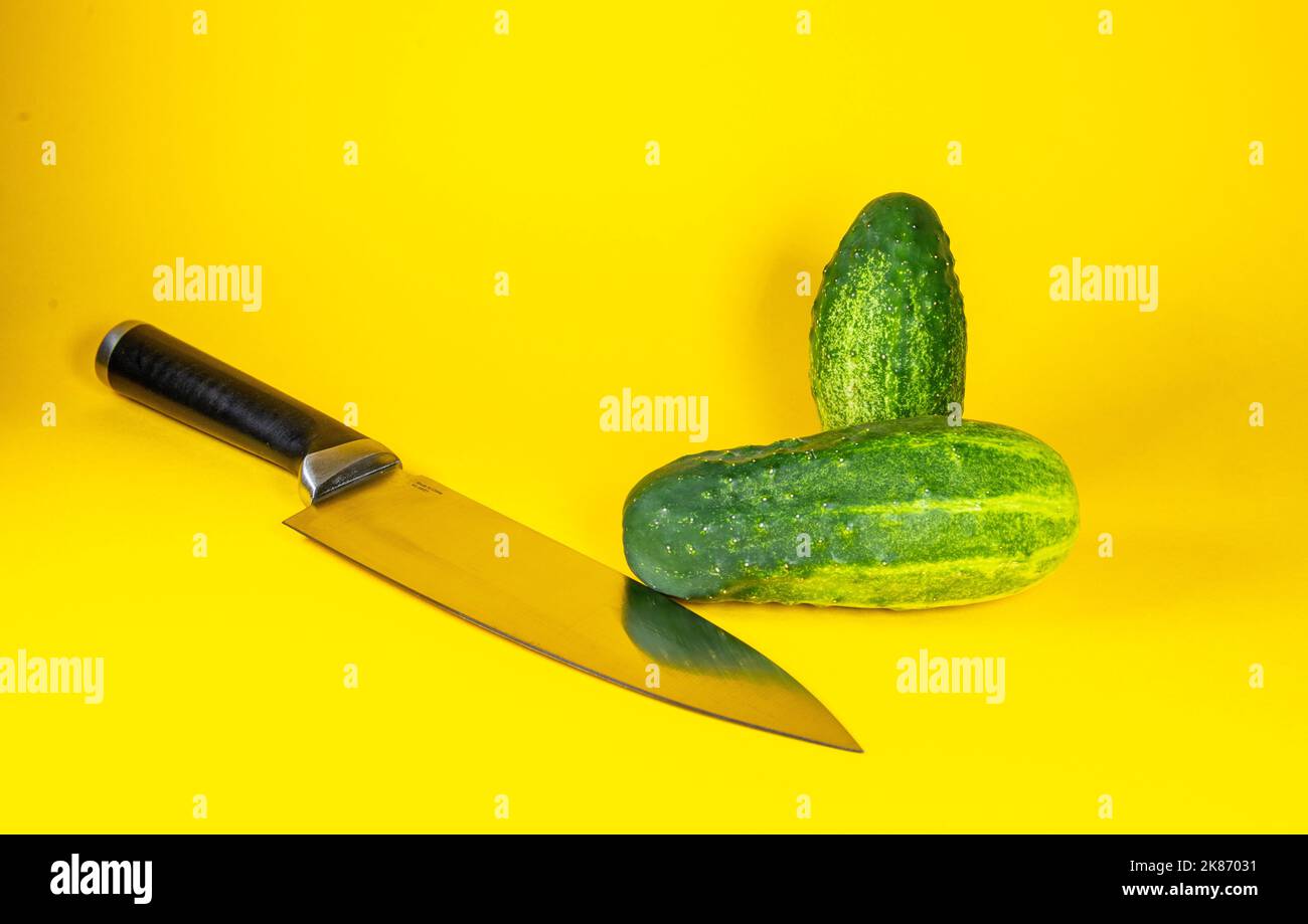 Two cucumbers with a knife isolated on the yellow background Stock ...