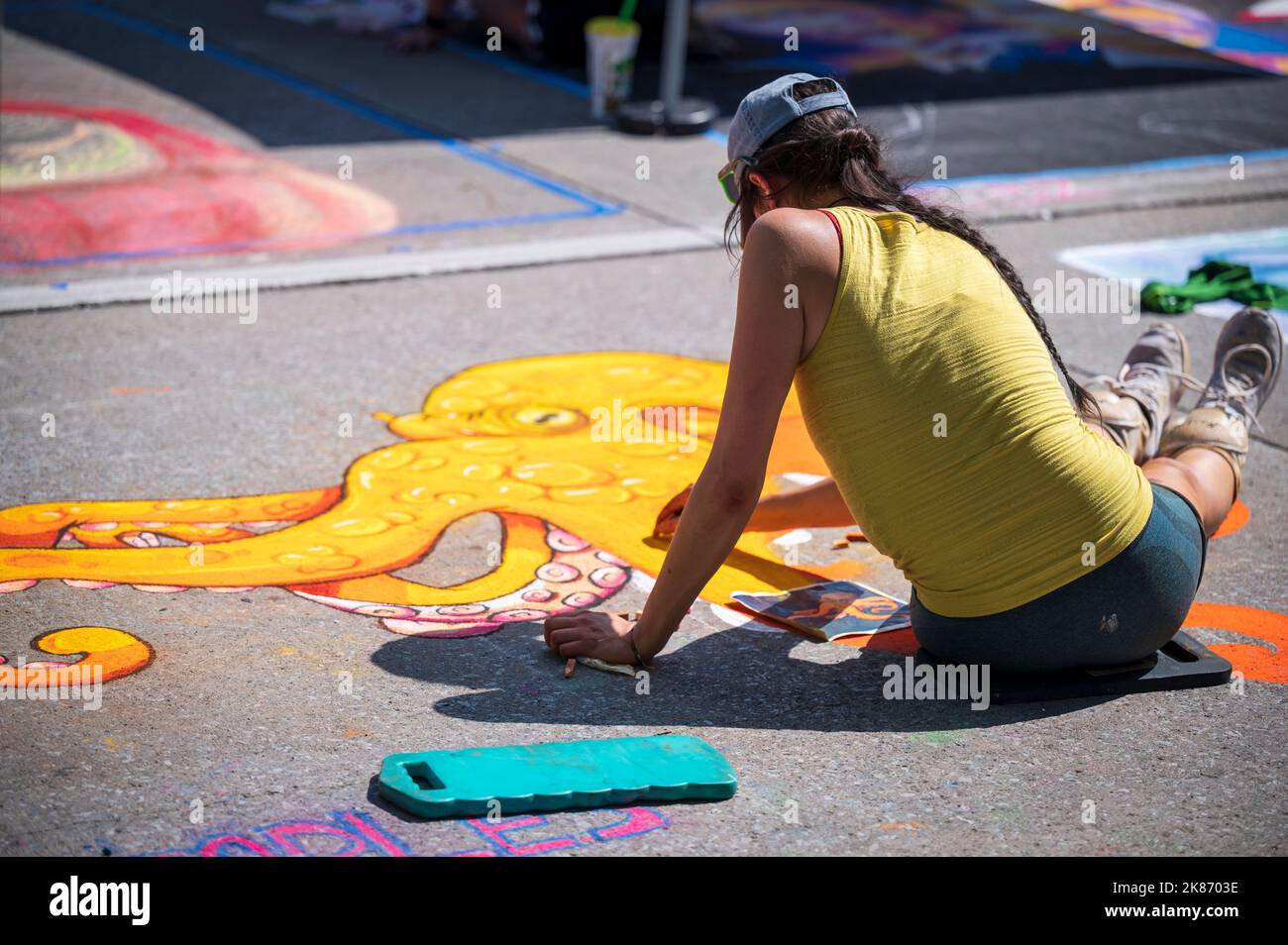 A female from behind drawing on the ground with chalk in Fort Wayne ...