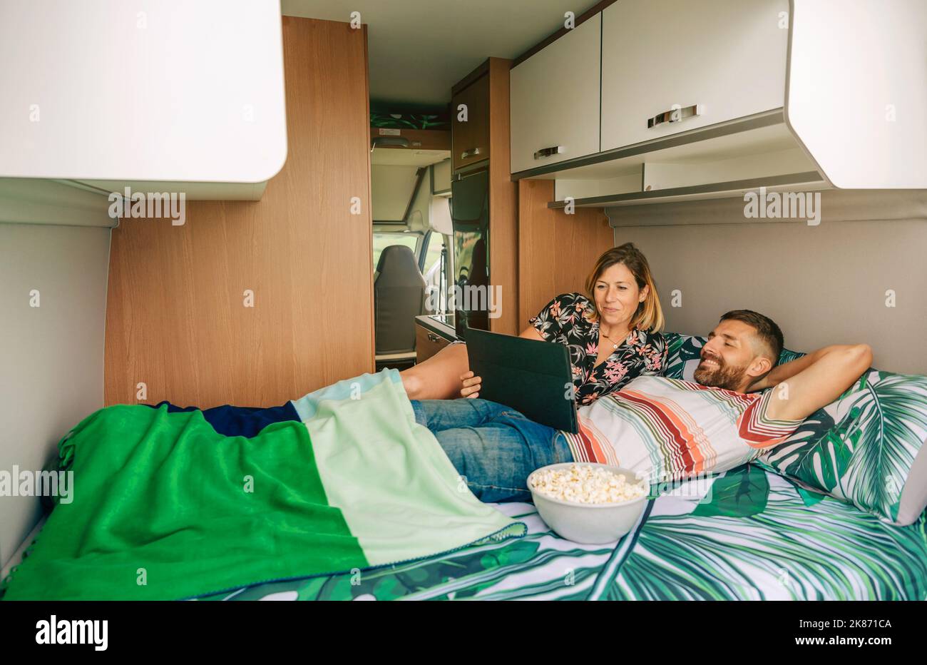 Couple watching a movie on the tablet lying on the bed of their camper ...