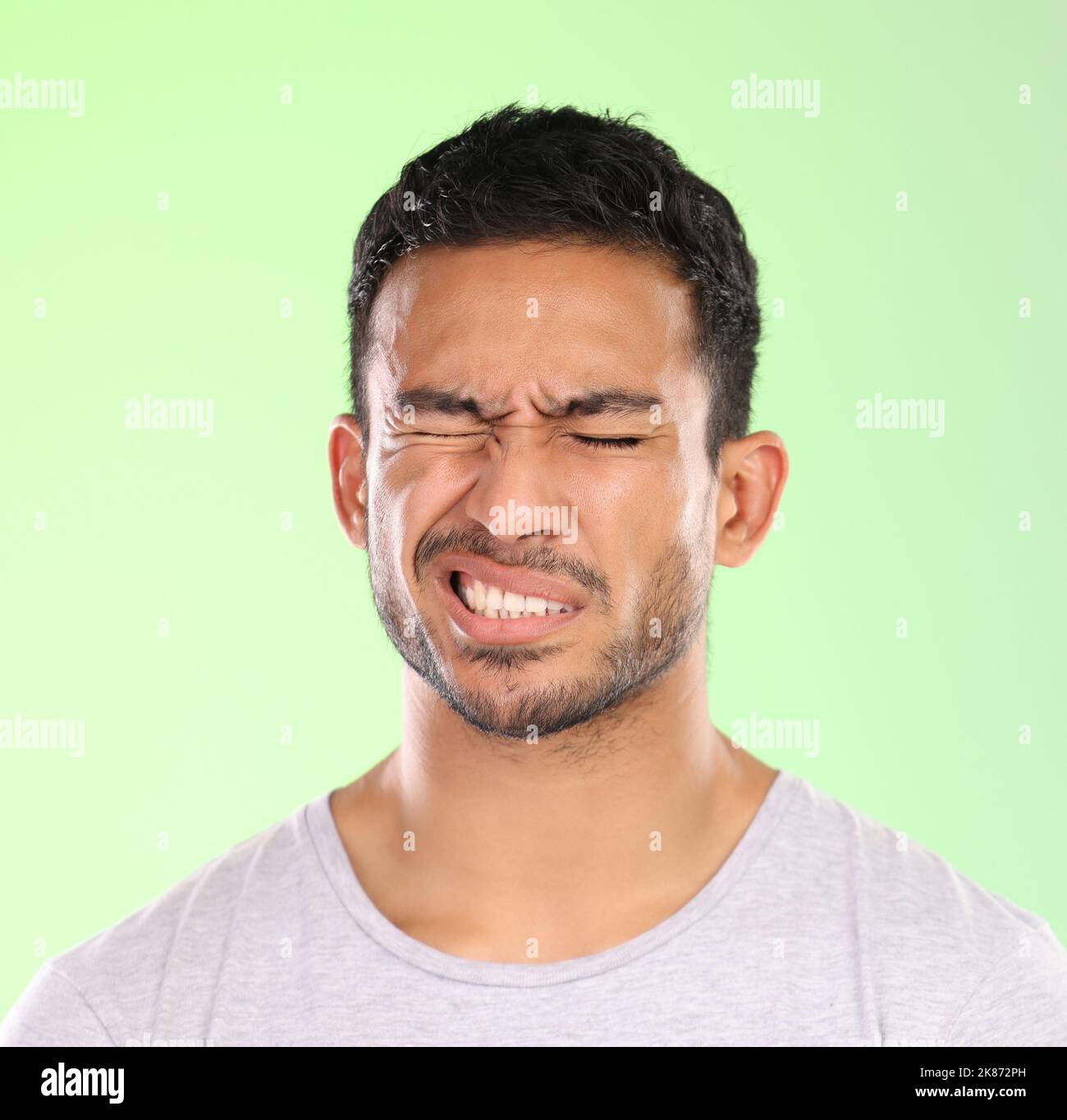 Oh no. a handsome young man making a face against a green background in ...