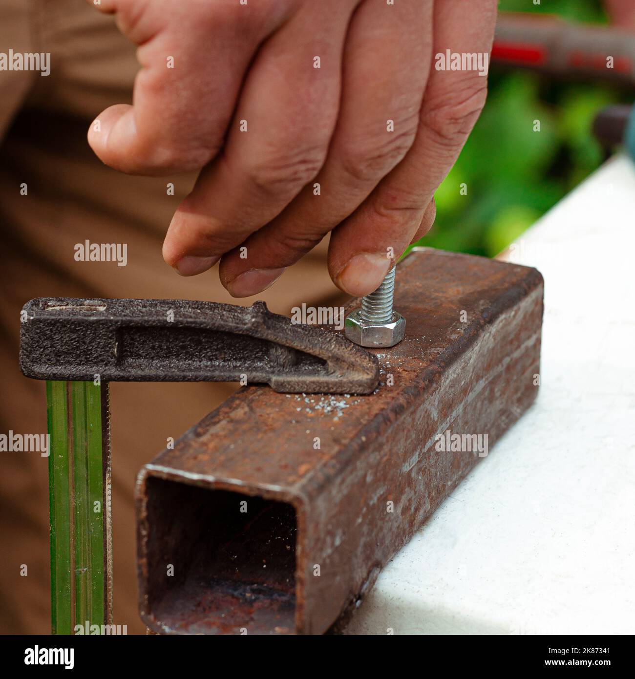 A man's hand screws a bolt into a metal nut. Working with metal Stock ...