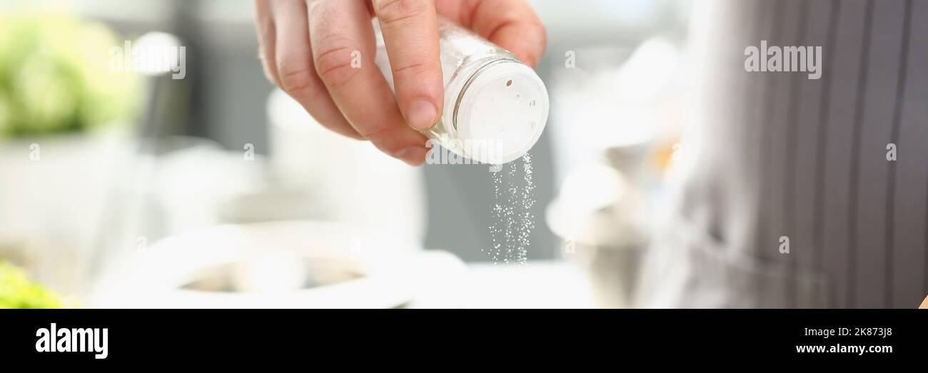 Professional cook hold saltcellar and add salt to soup against kitchen ...