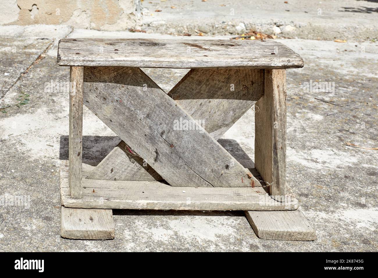Very old wooden stool, in a concrete paved courtyard Stock Photo - Alamy