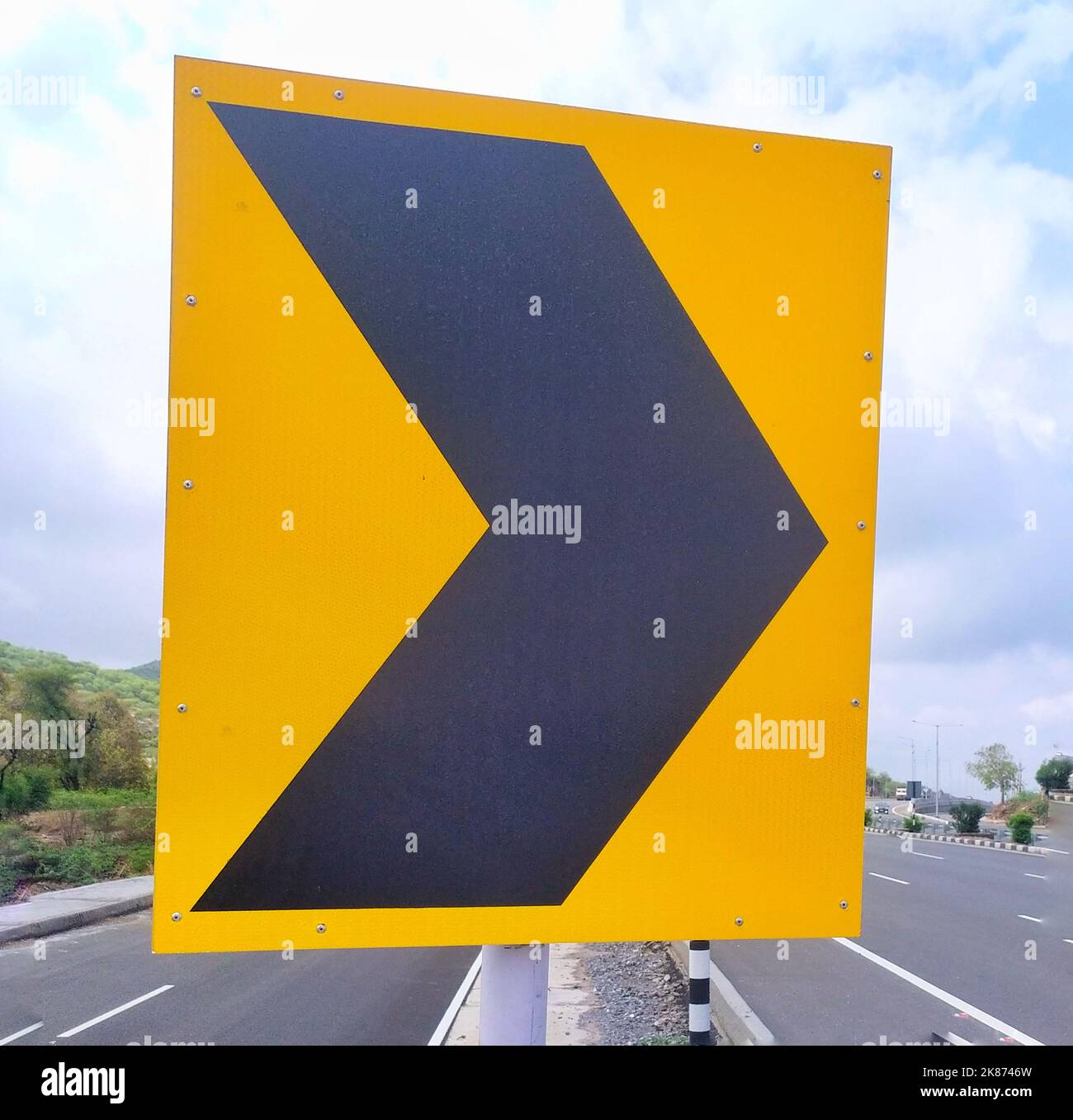 A black and yellow chevron sign warning about dangerous curves, medians ...