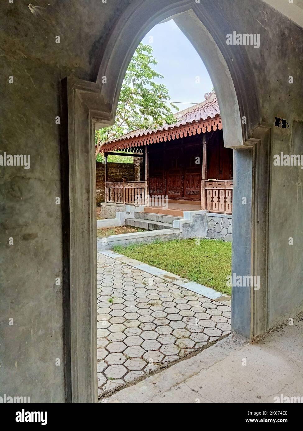 facade of a traditional Javanese wooden house framed by a concrete gate ...