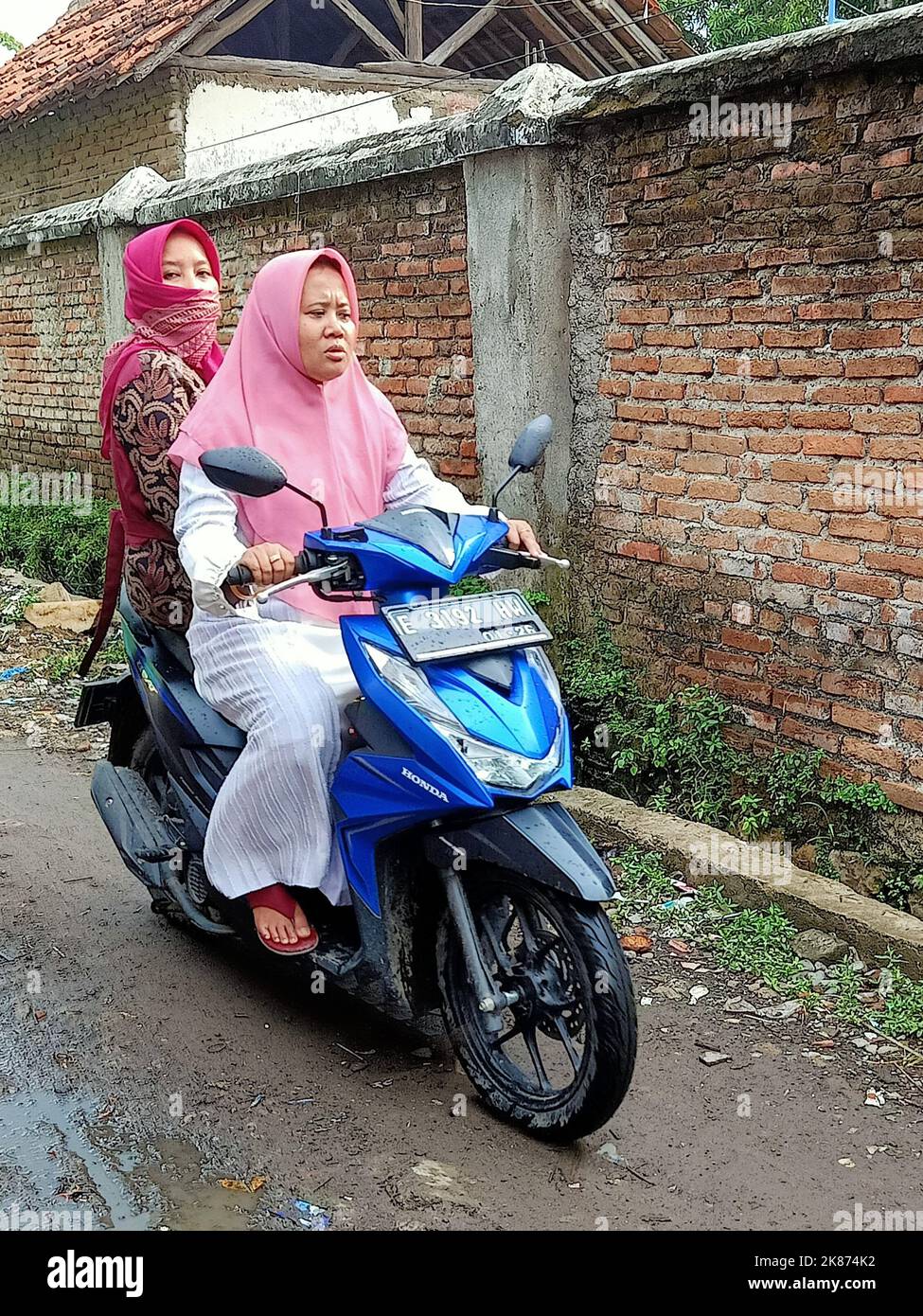 Two moslem women who wear headscarves are riding a motorcycle in an ...