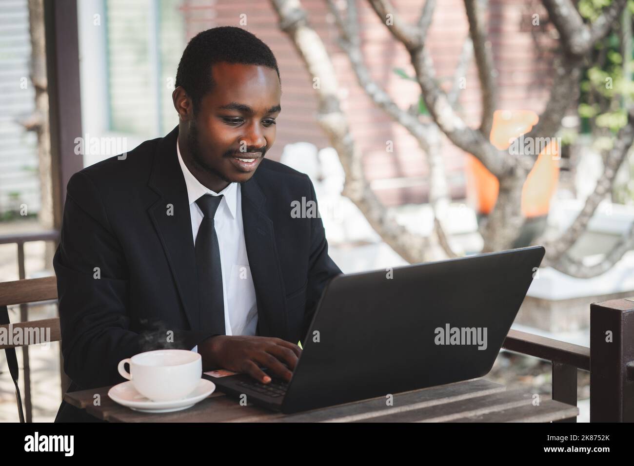 Happy african businessman in a suit use business laptop at coffee shop ...