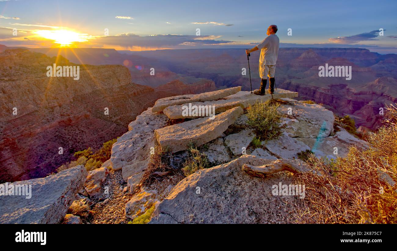 A hiker watching the sun go down west of Moran Point at Grand Canyon ...